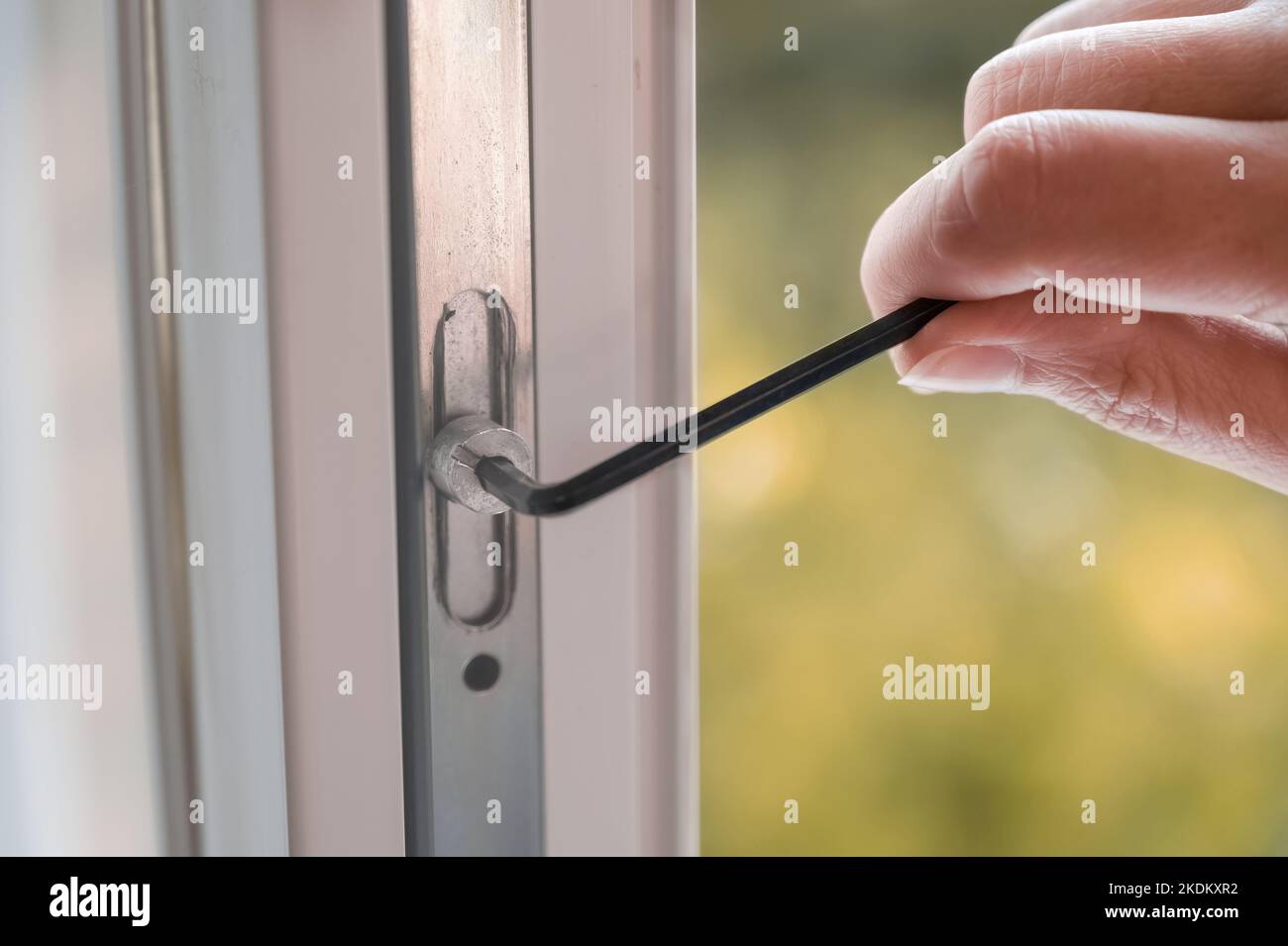handyman adjusts the pvc window in the room. a worker uses a hexagon to ...