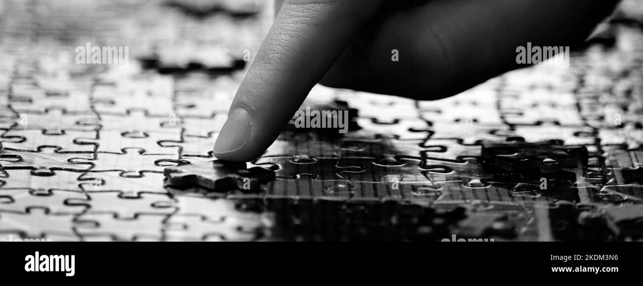 Hand with finger completing a jigsaw puzzle for fun and achievement ...