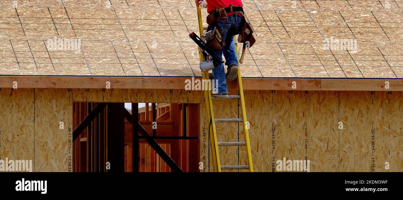 Construction worker climbing up ladder work site on home being built ...