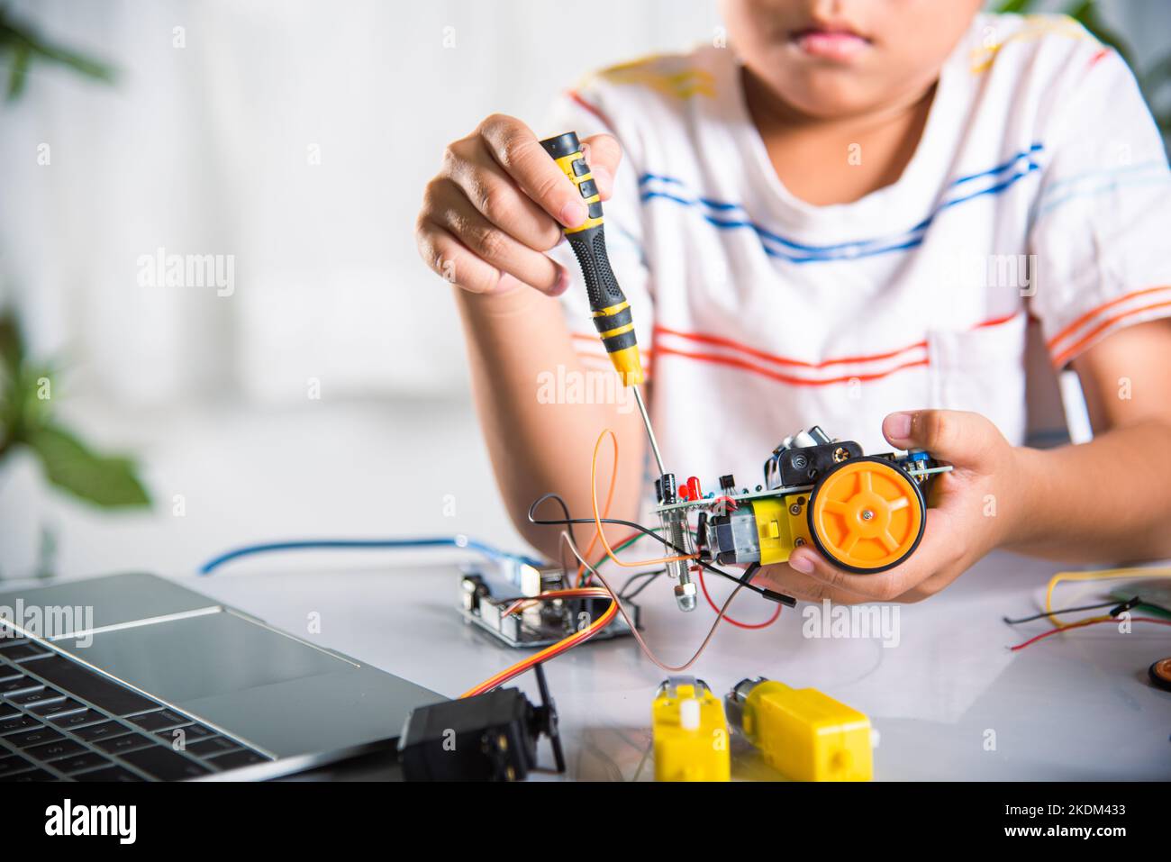 Asian kid boy assembling the Arduino robot car homework project at home ...