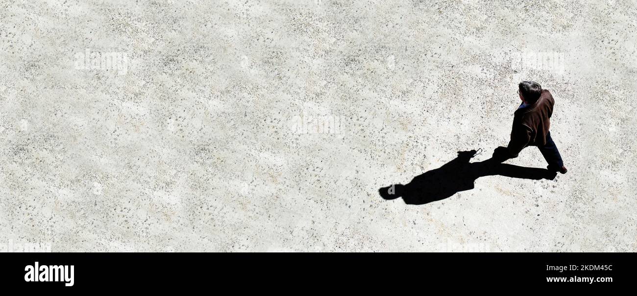 Man walking with dark shadow across cement walkway representing mystery ...