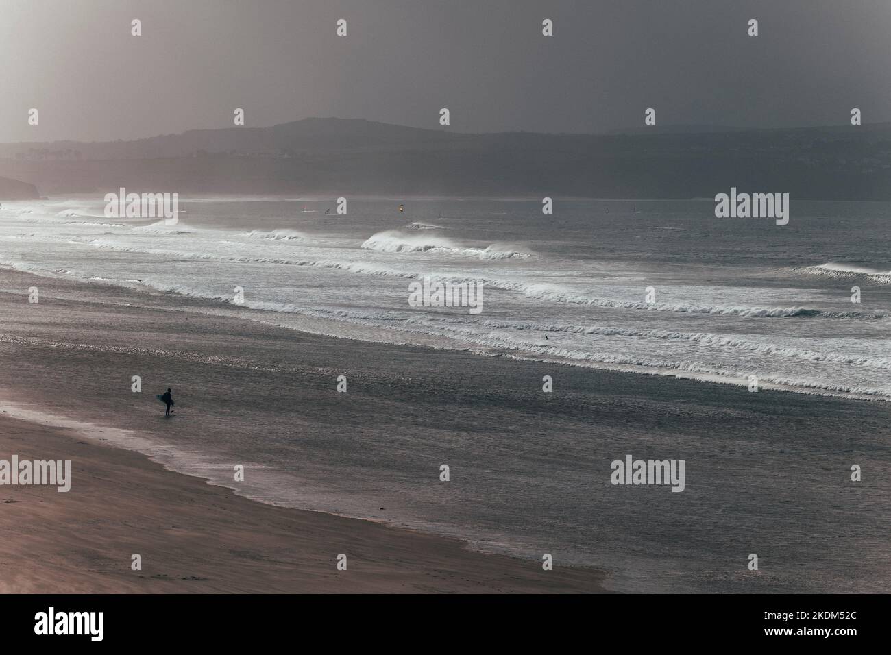 Surfer making his way out into the sea on as misty storm day. Moody St ...