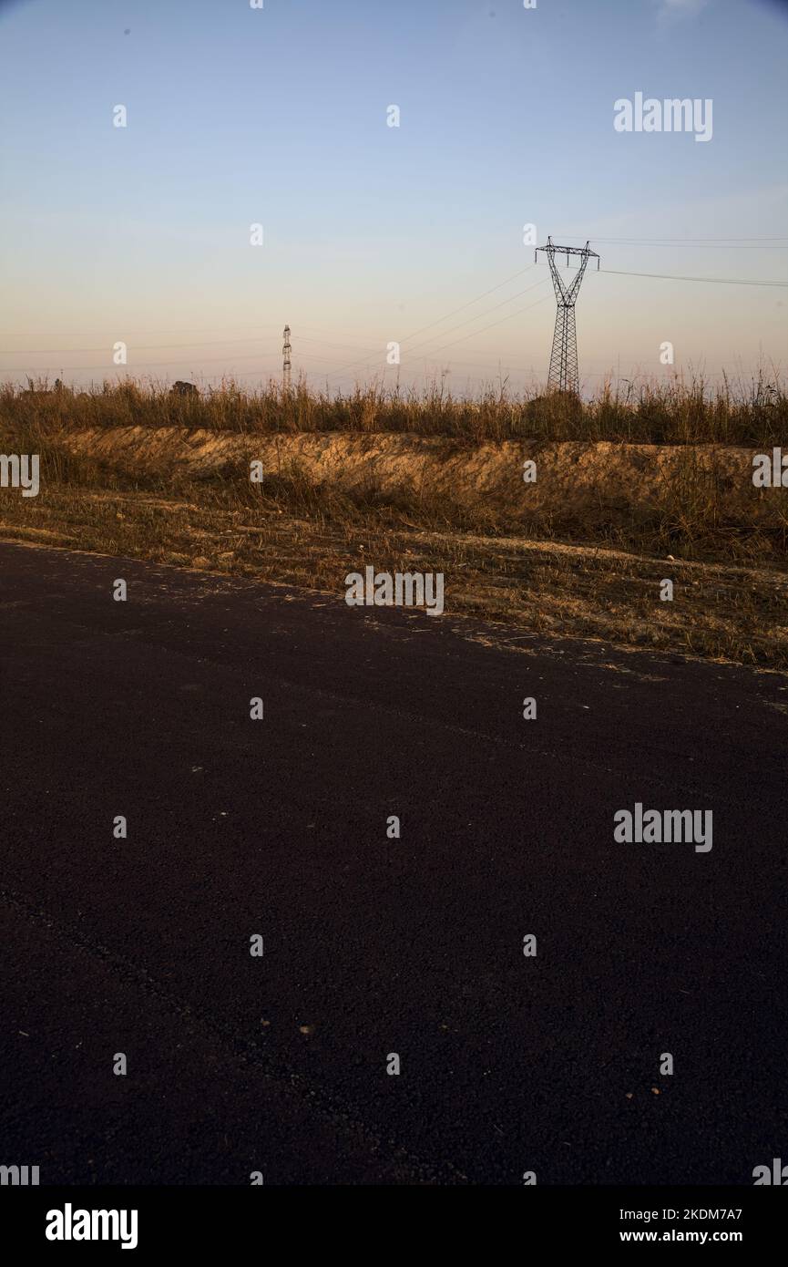 Electricity pylon in a field behind an embankment at the edge of a ...