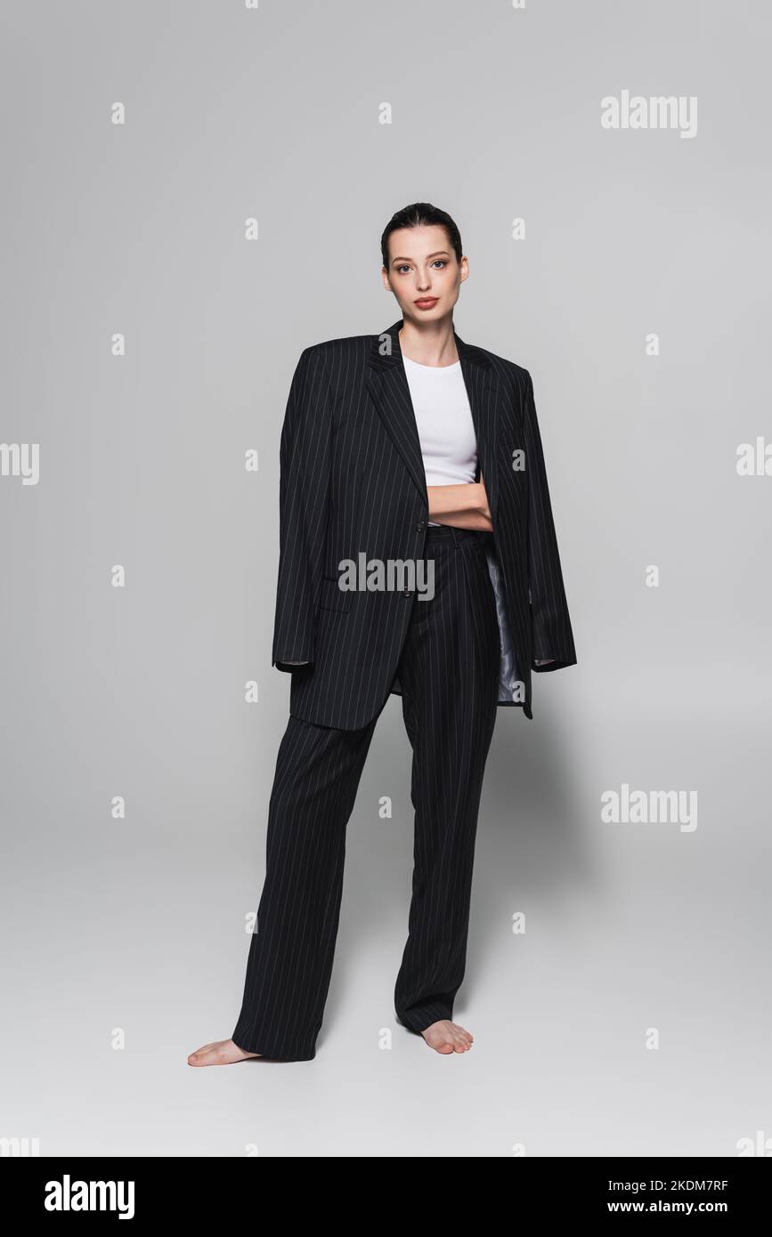 Full length of barefoot model in suit posing on grey background Stock ...