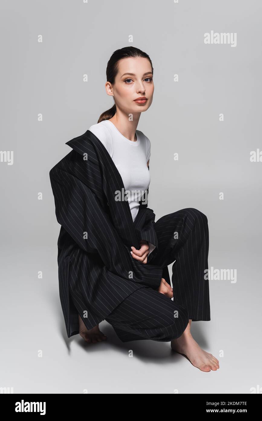 Fashionable and barefoot model in suit posing on grey background Stock ...