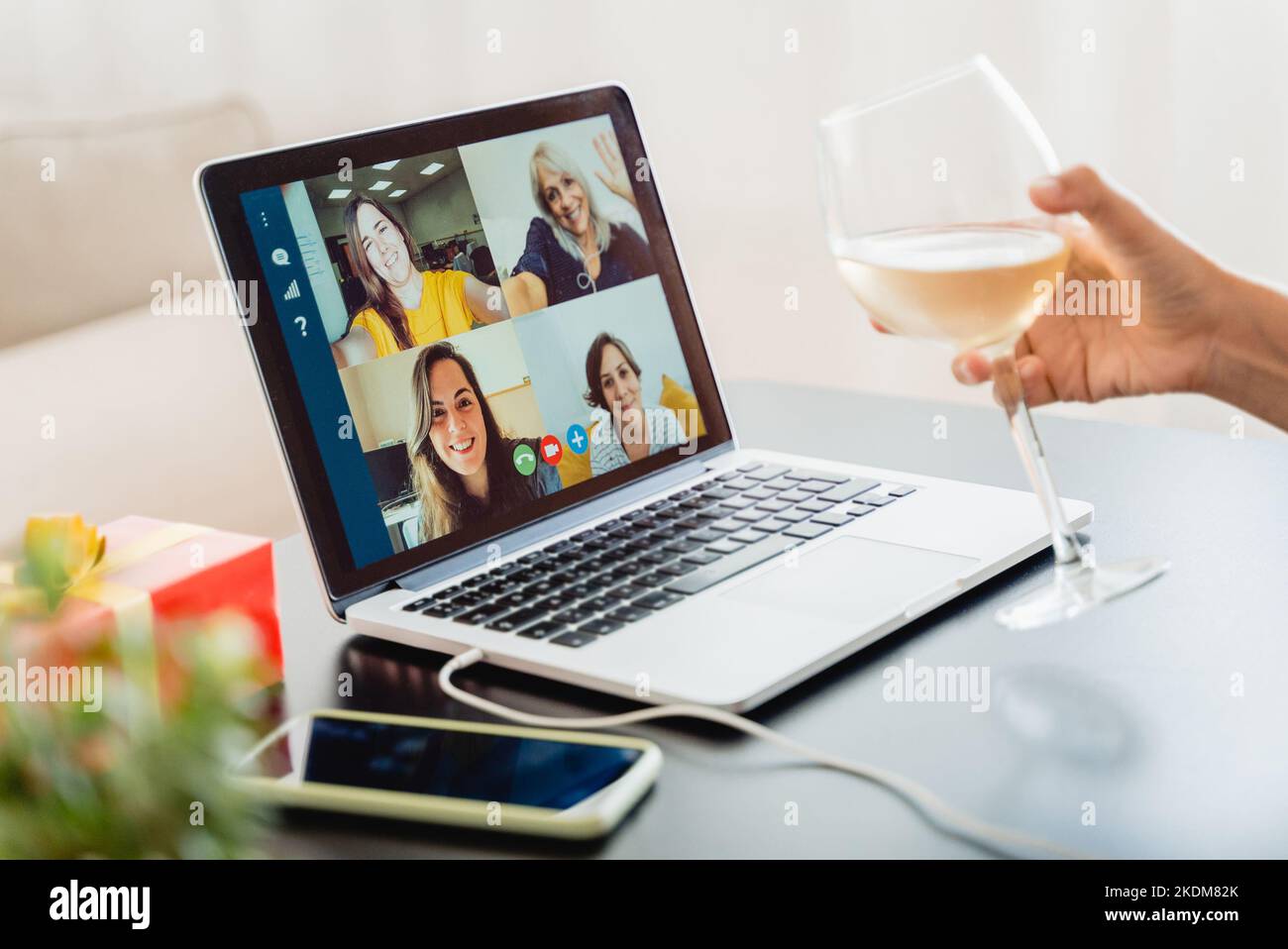 Young woman celebrating with wine in video call meeting with family ...