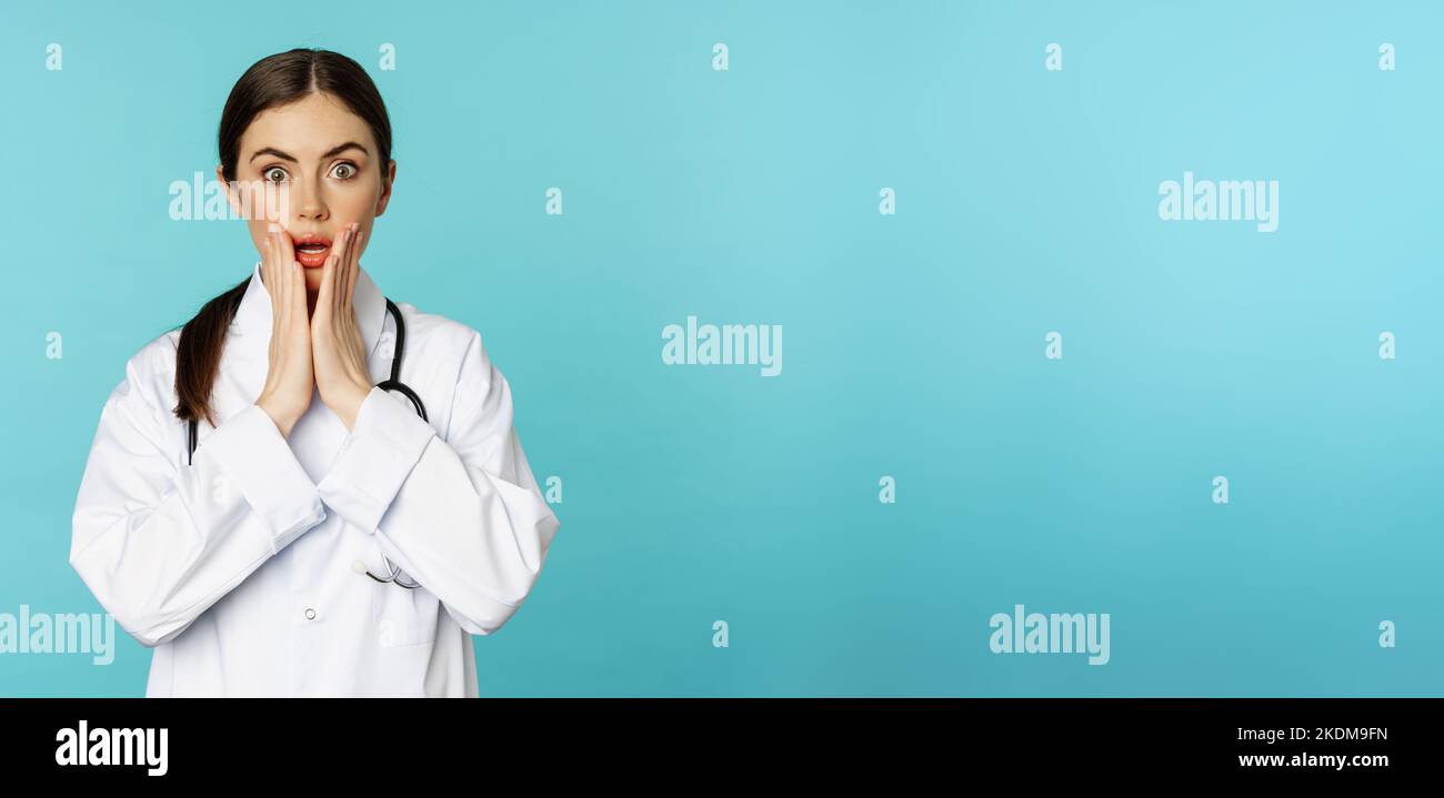 Portrait of shocked woman doctor, female hospital intern in white coat ...
