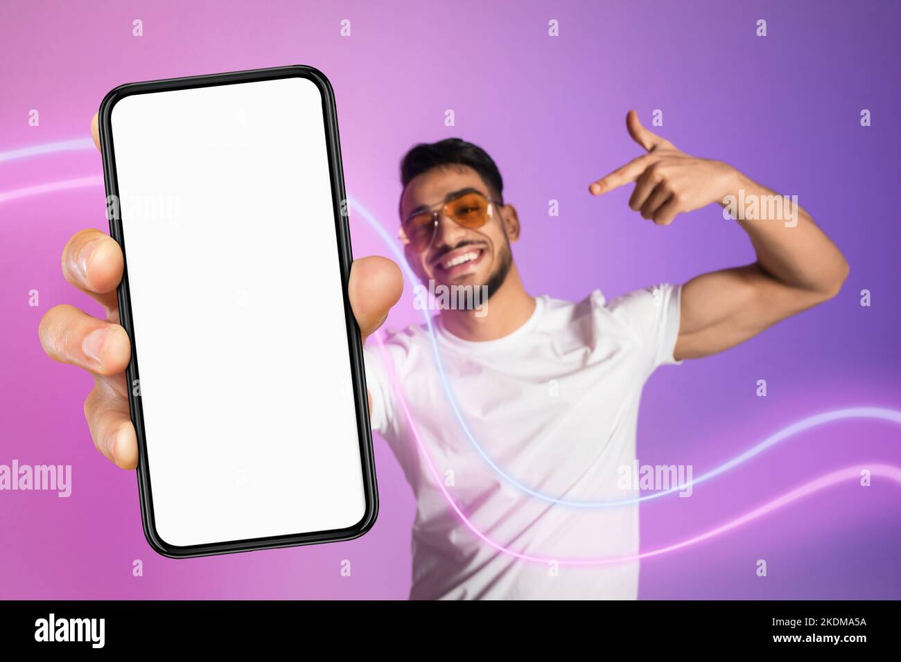 Cheerful arab guy in sunglasses pointing at modern cell phone Stock ...
