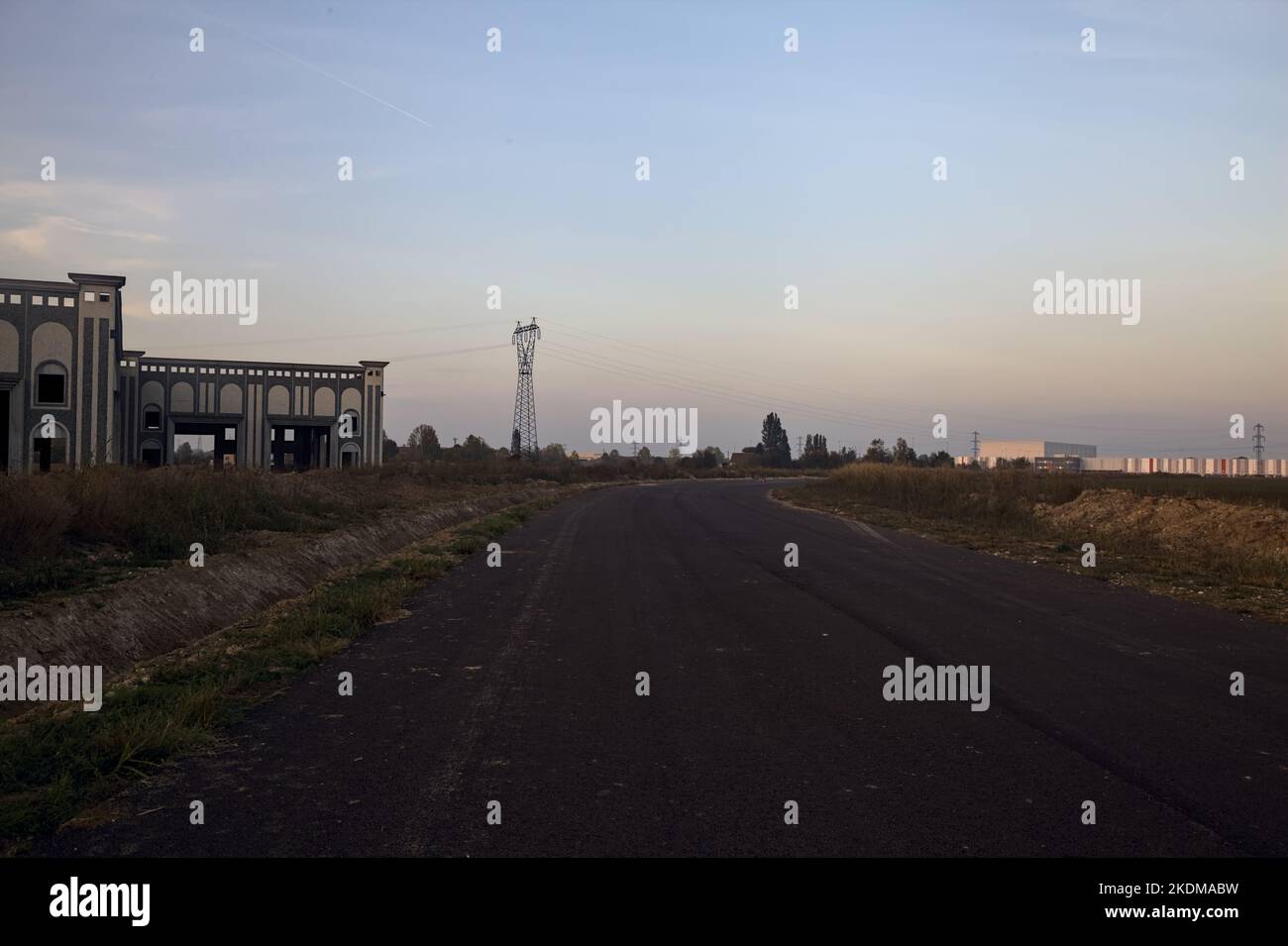 Empty road with abandoned warehouses and pylons at sunset Stock Photo ...