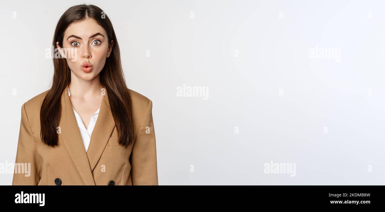 Portrait of office lady at workplace, looking surprised and curious ...