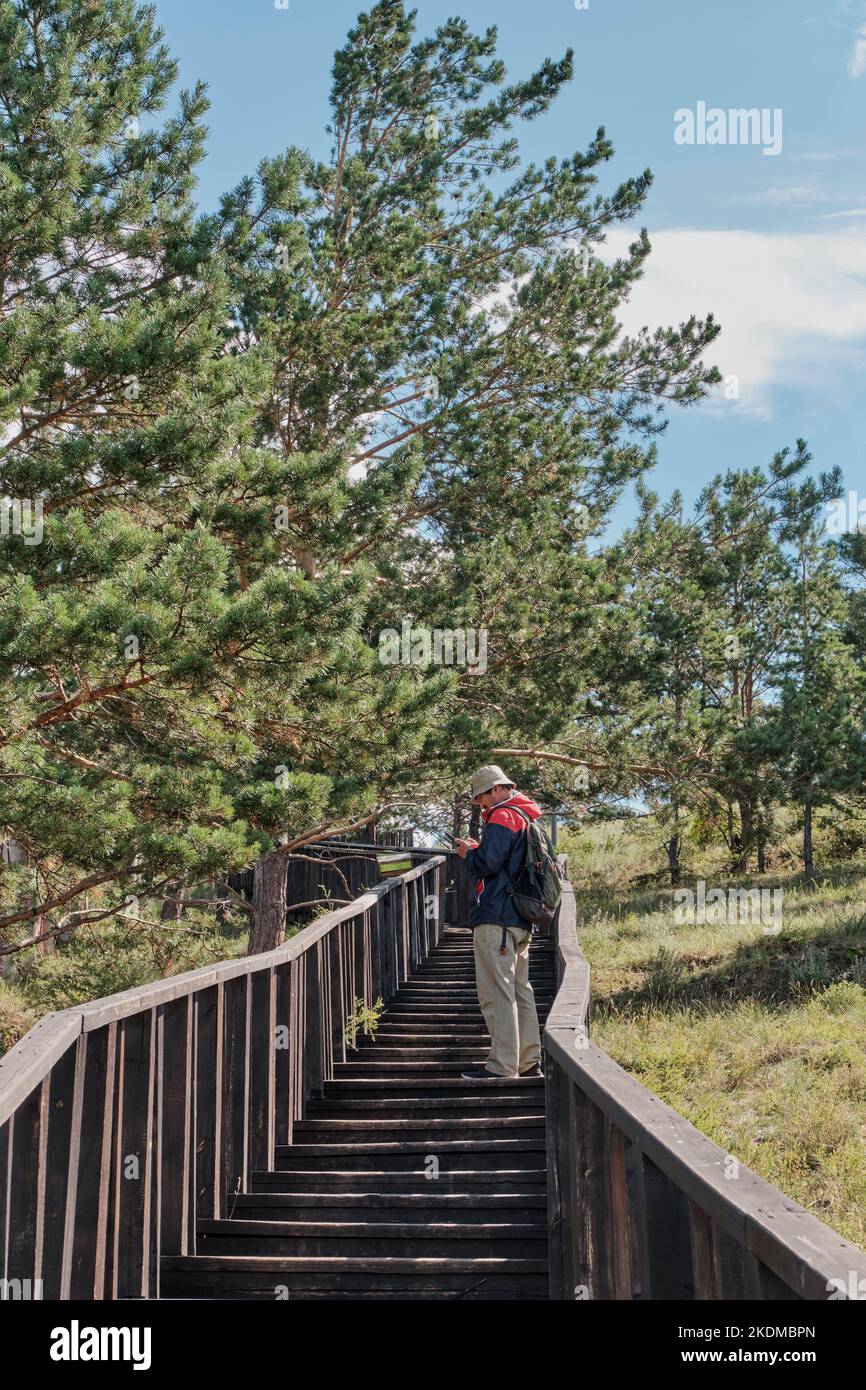 Asian backpacker with cell phone on wooden stairs in park area Stock ...