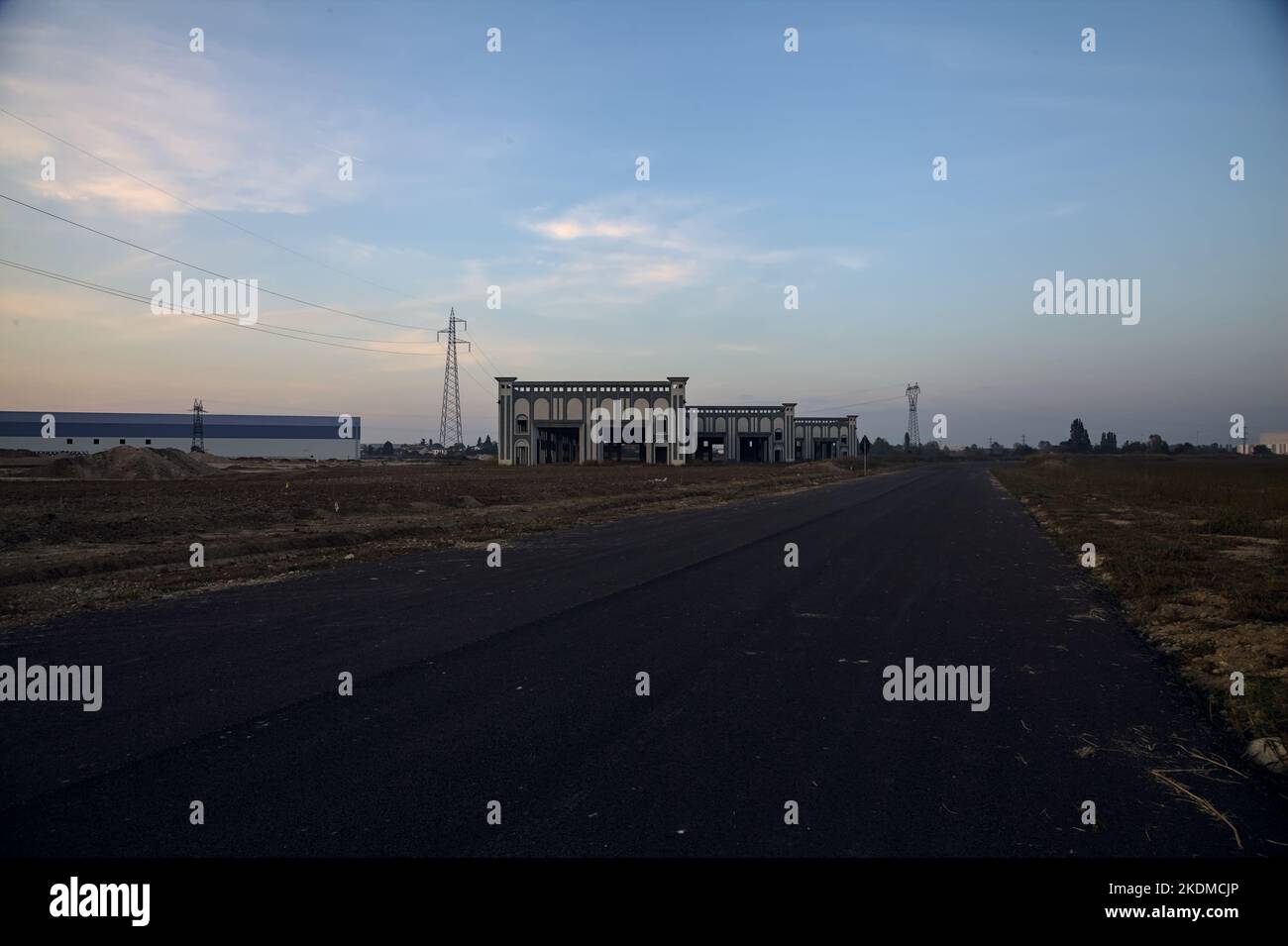 Empty road with abandoned warehouses and pylons at sunset Stock Photo ...