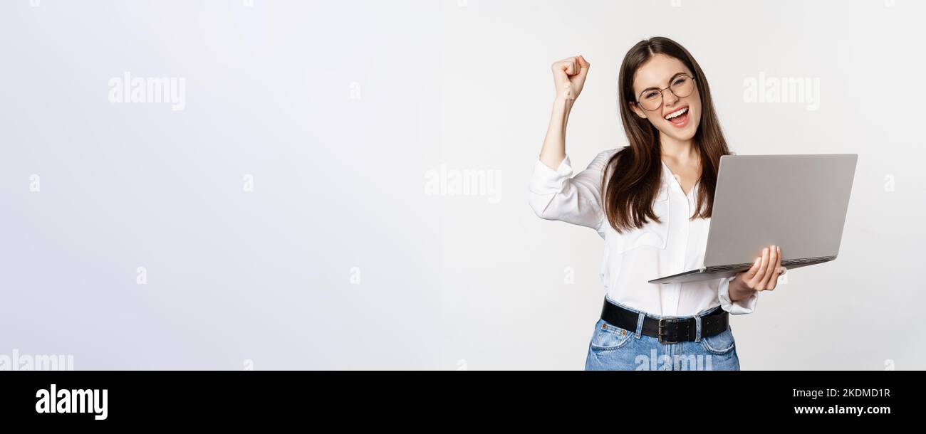 Enthusiastic office woman, businesswoman holding laptop and shouting ...