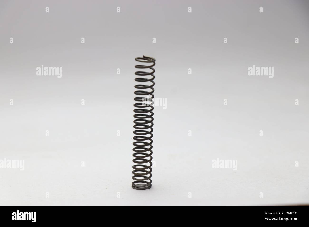 Steel compression coil spring standing on its own isolated on white ...