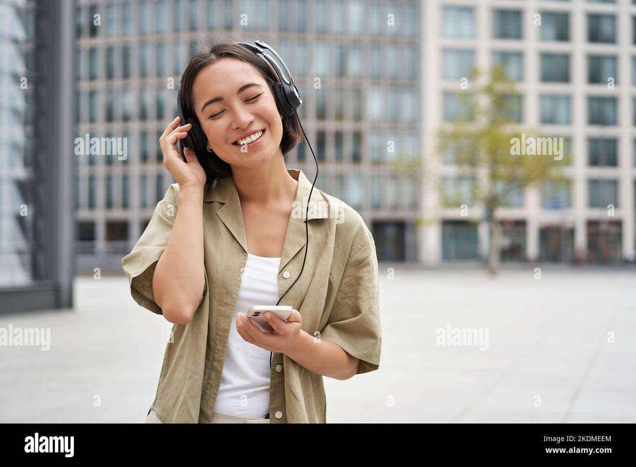 Streaming services concept. Happy asian girl listens music in ...