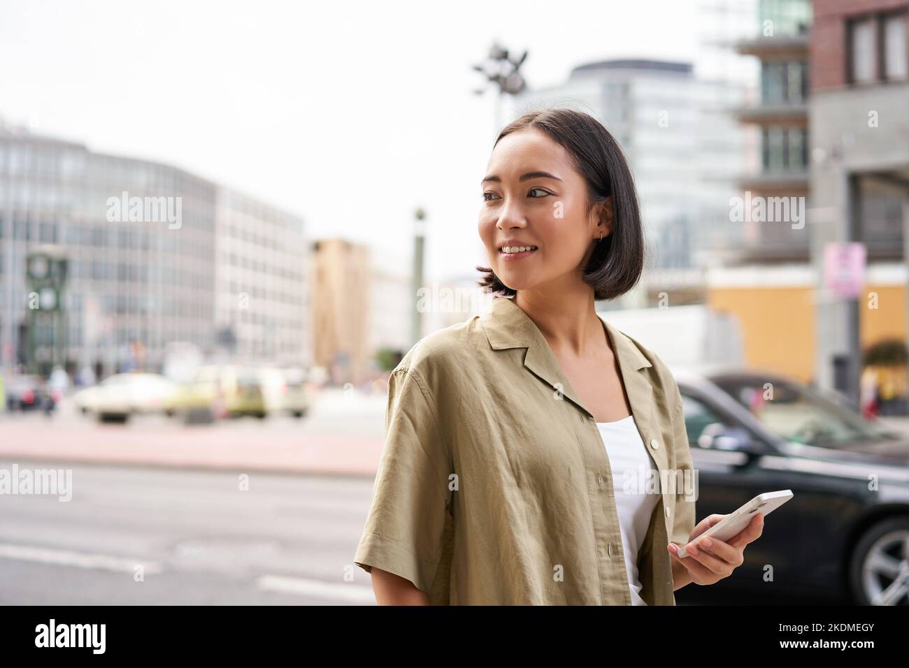 Young woman walking down the city street, turn behind, using map app ...