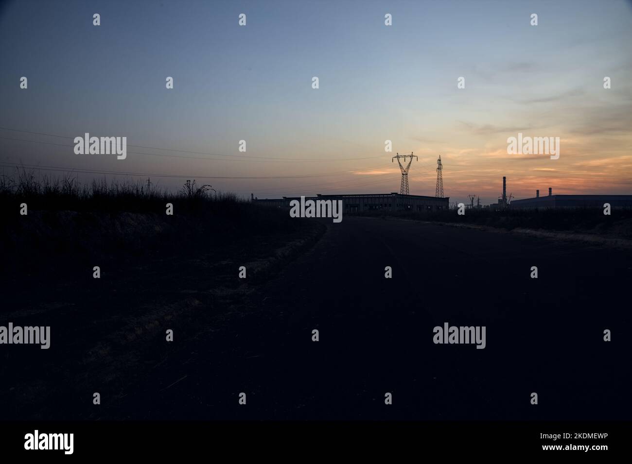 Empty road with abandoned warehouses and pylons at sunset Stock Photo ...