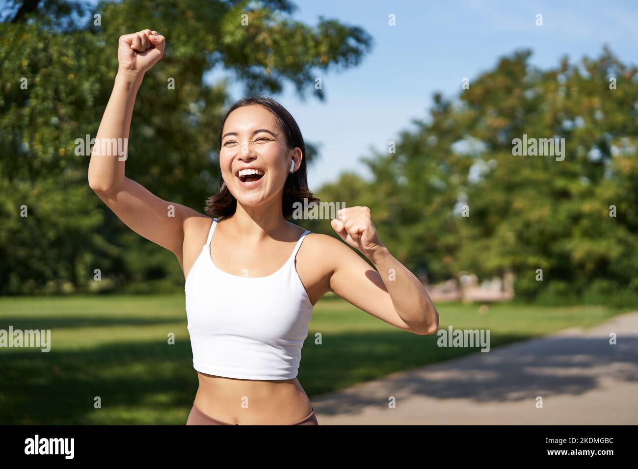 Happy fitness girl achieve goal, finish marathon, running with hands up ...