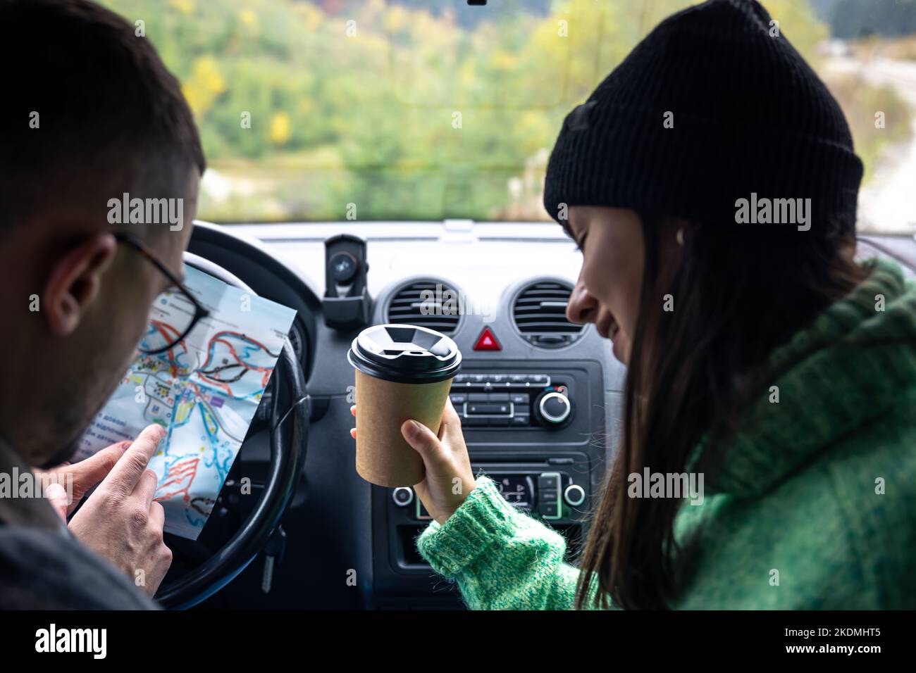 A man and lady holding and looking at paper map, sitting inside car ...