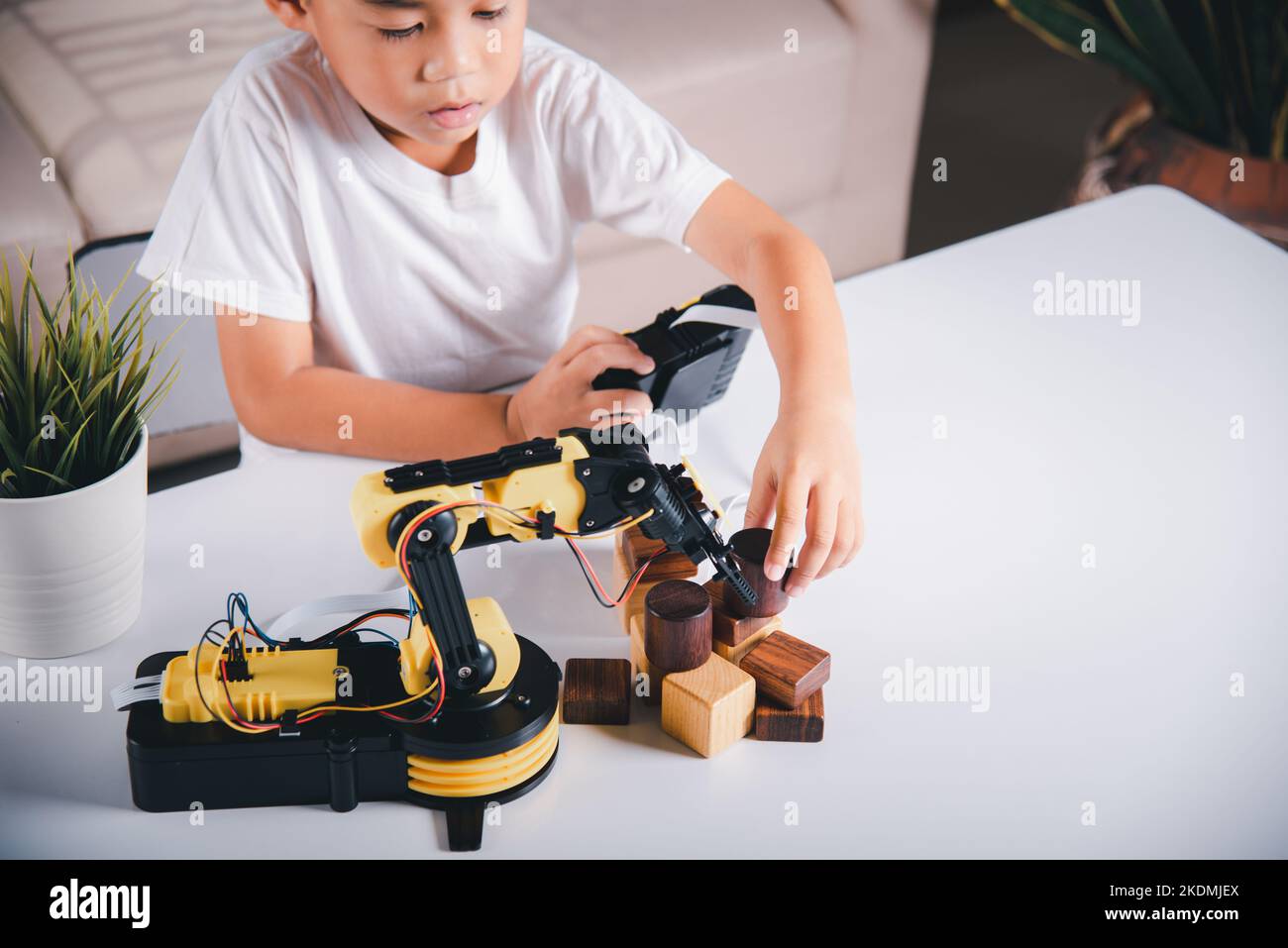 Happy Asian little kid boy using remote control playing robotic machine ...