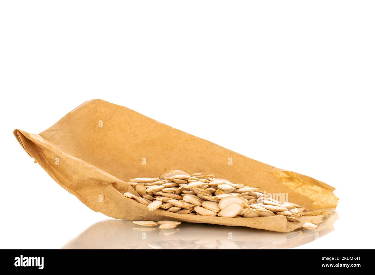 Unpeeled raw pumpkin seeds on a paper bag, macro, isolated on white ...