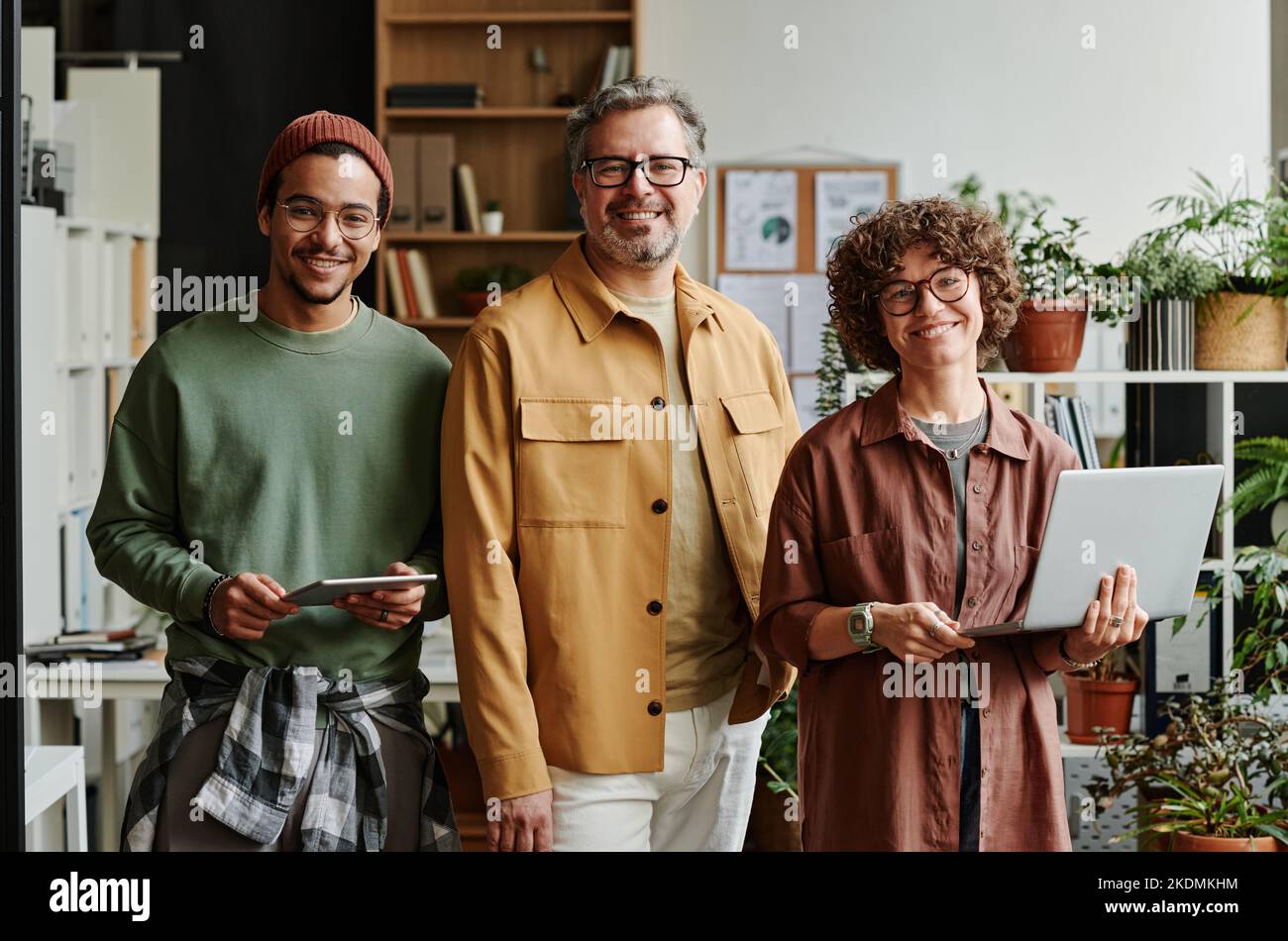 Two young intercultural IT engineers with mobile gadgets standing by ...