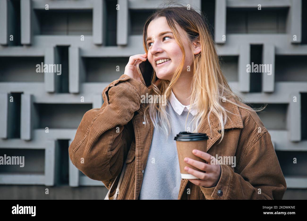 A young woman talking on the phone against a geometric background of ...