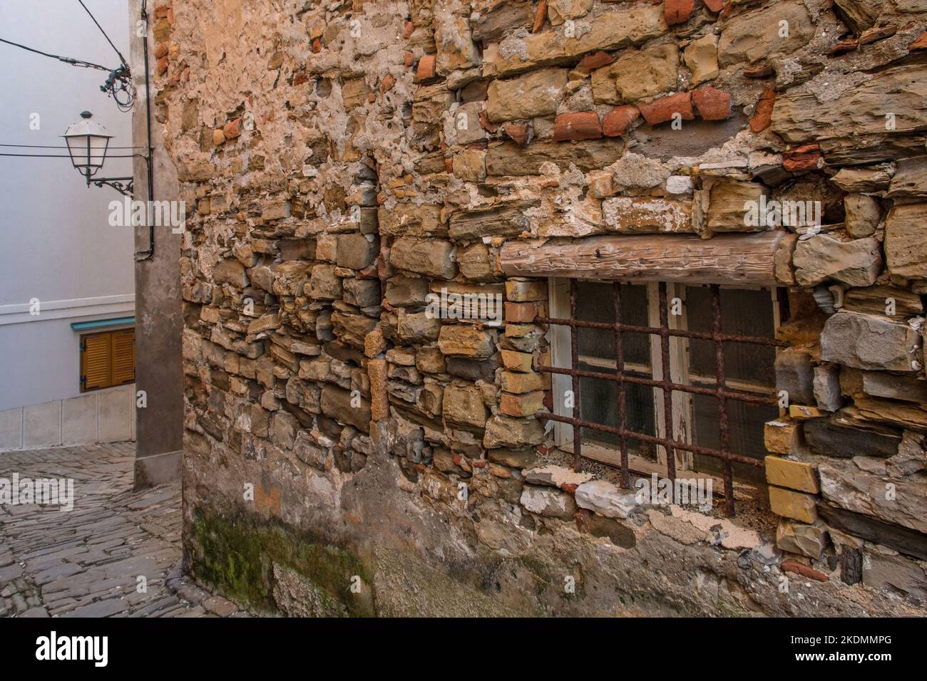 A barred window in an old stone residential building in the historic ...