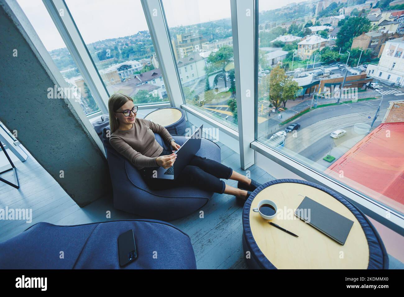 A beautiful female student works on a laptop while sitting on a bean ...