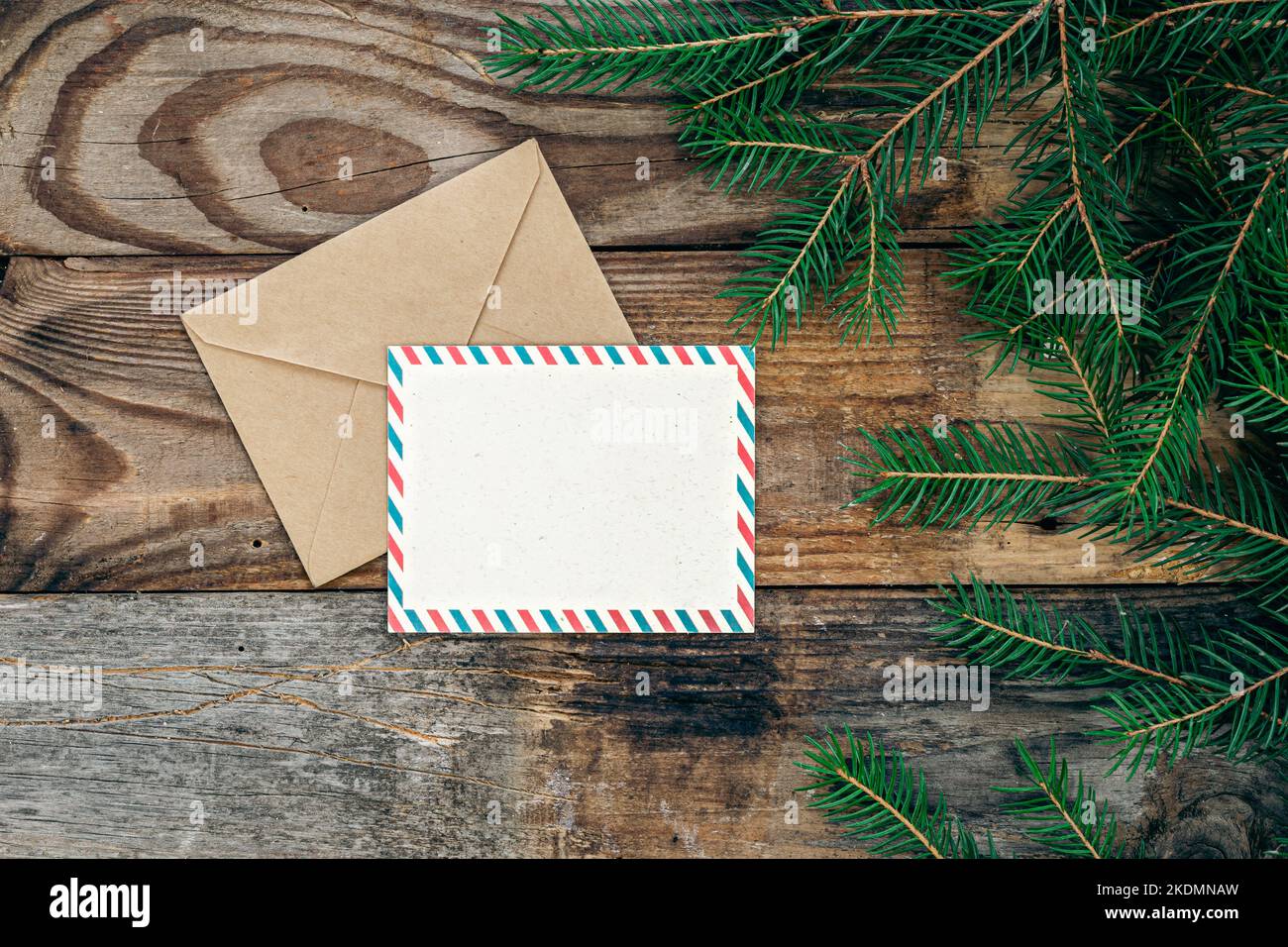 Blank postcard, envelope and fir branches on a wooden background, flat ...