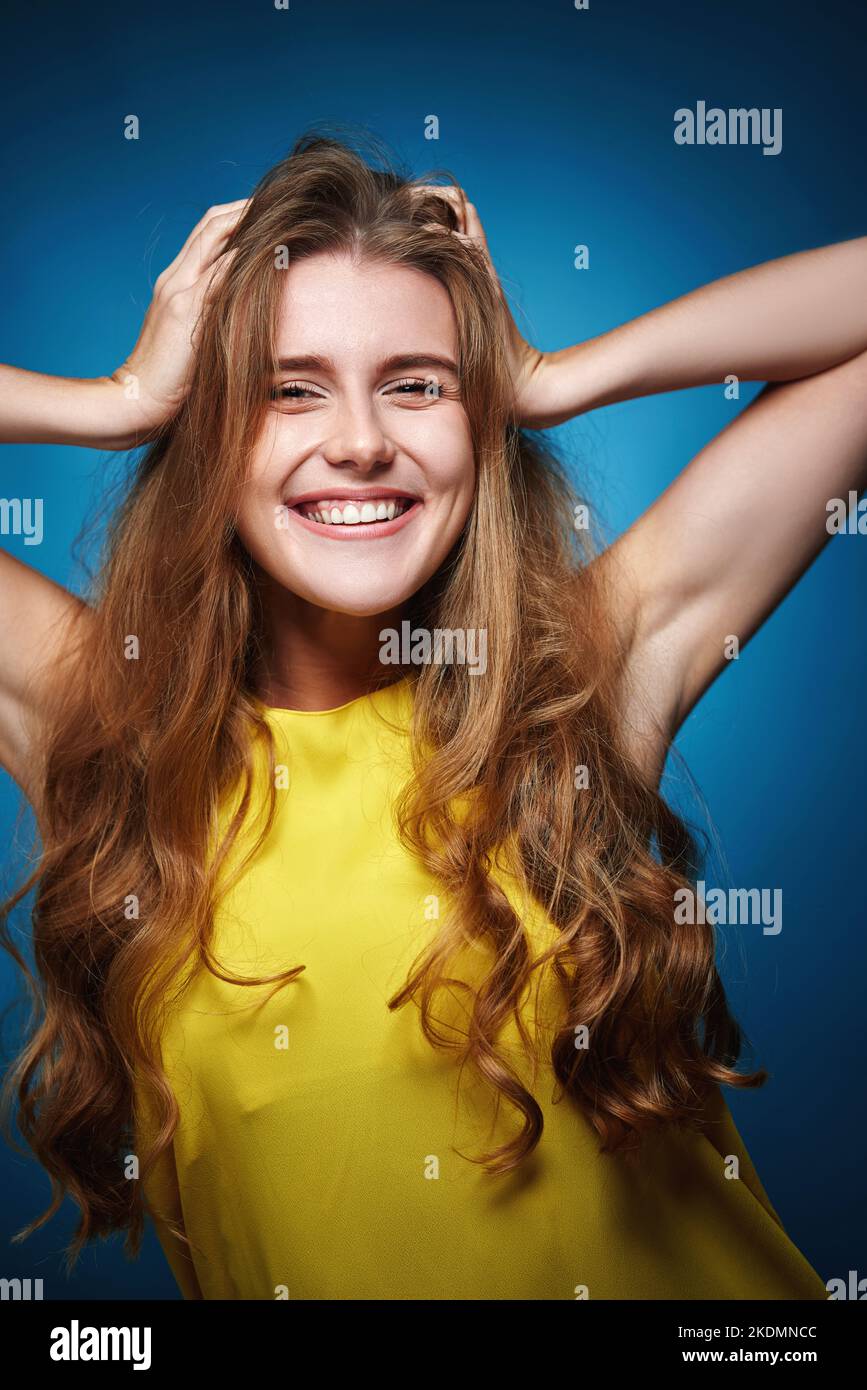happy woman with strong healthy curly hair dancing on blue background ...