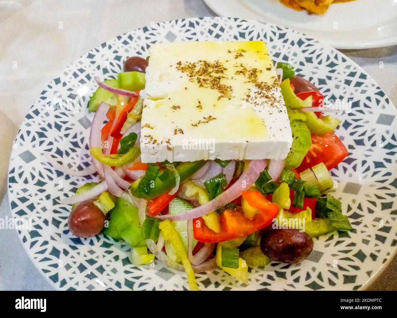 Colouful Greek sallad topped with a big slice of feta cheese from a ...