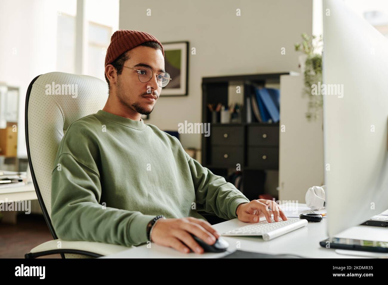 Professional IT engineer in eyeglasses looking at computer screen while ...