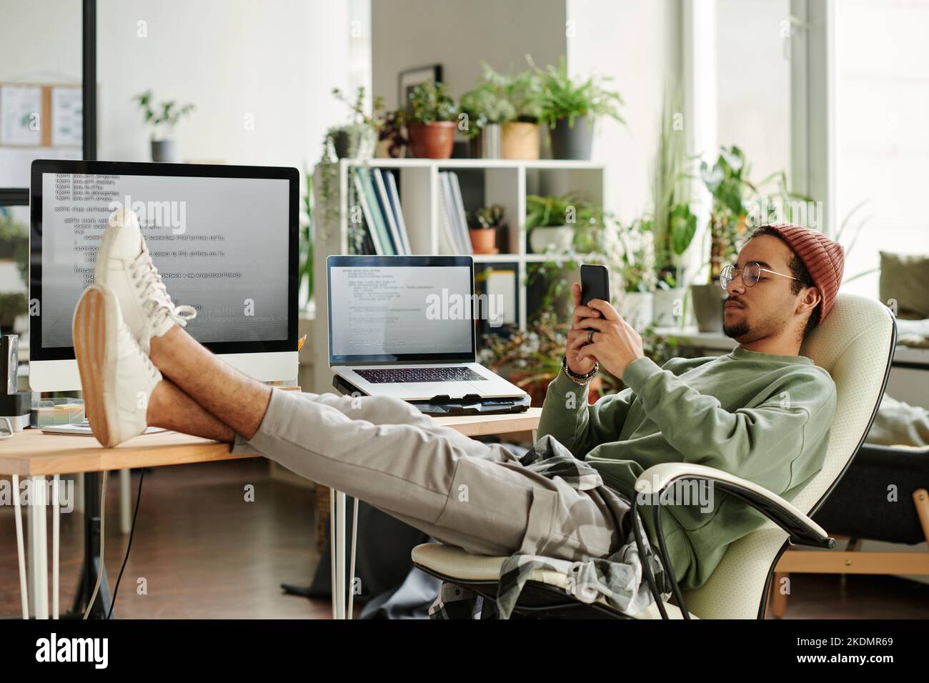Young restful IT engineer sitting in armchair by workplace with ...