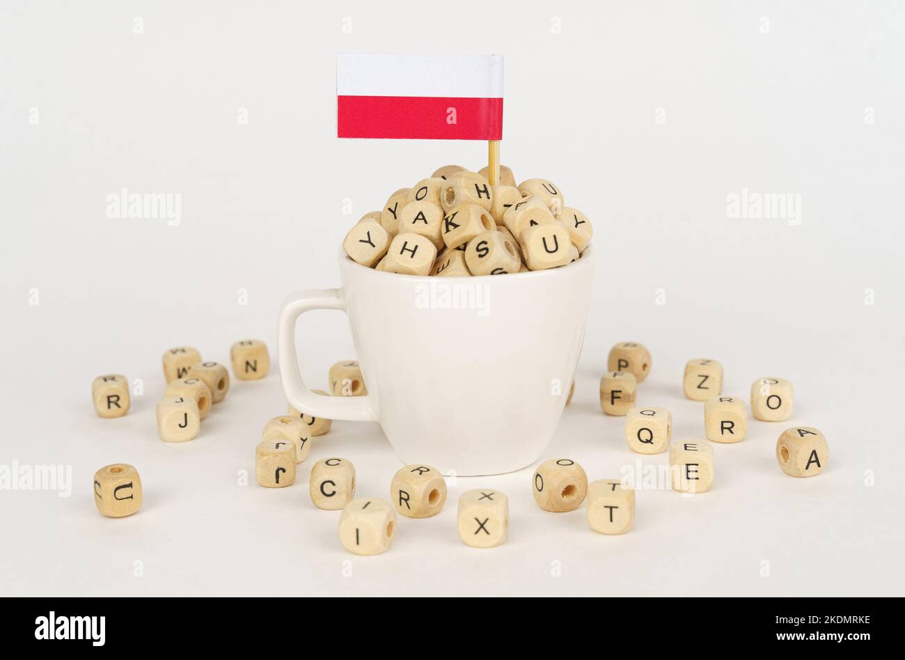 The flag of Poland sticks out of a cup with cubes on which letters are ...