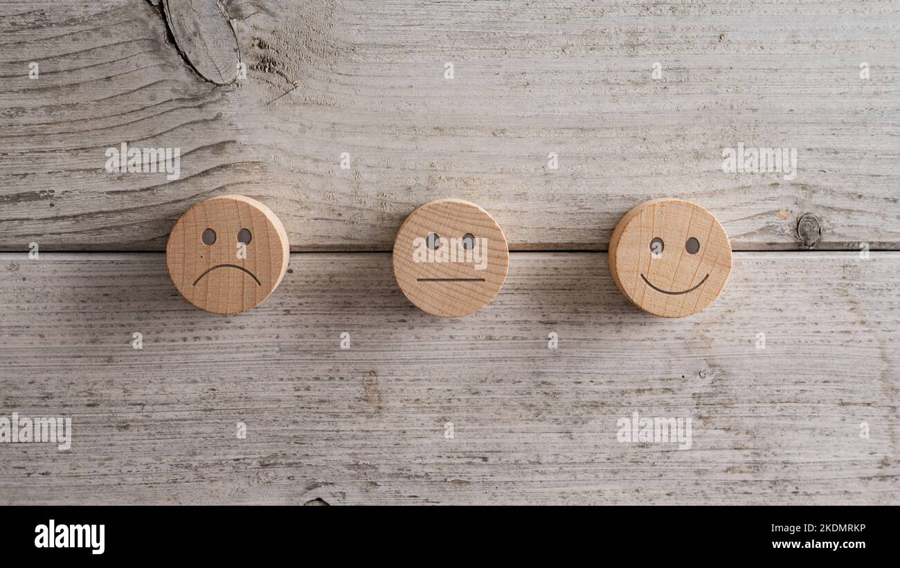 Three wooden cut circles each with a different emoticon - sad, average ...