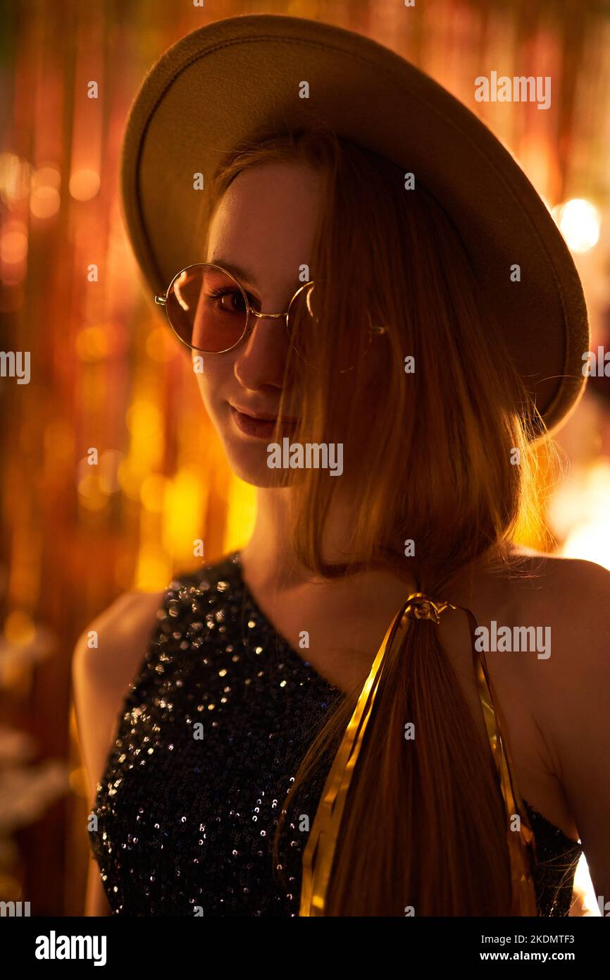 Happy and fun emotions during night party. Girl in hat and pink glasses ...