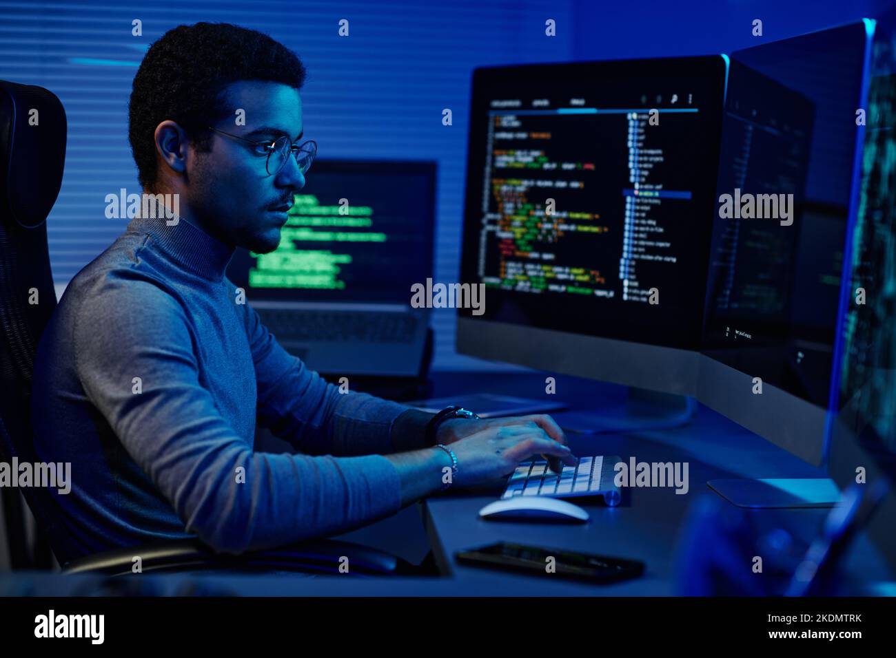 Young serious software developer typing on desktop keyboard while ...