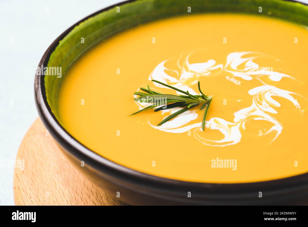 Closeup of pumpkin cream soup garnished with heavy cream and rosemary ...