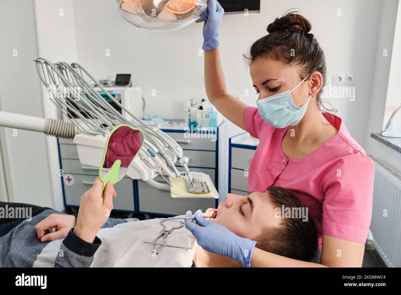 Dentist examines condition of teeth with help of dental mirror in ...