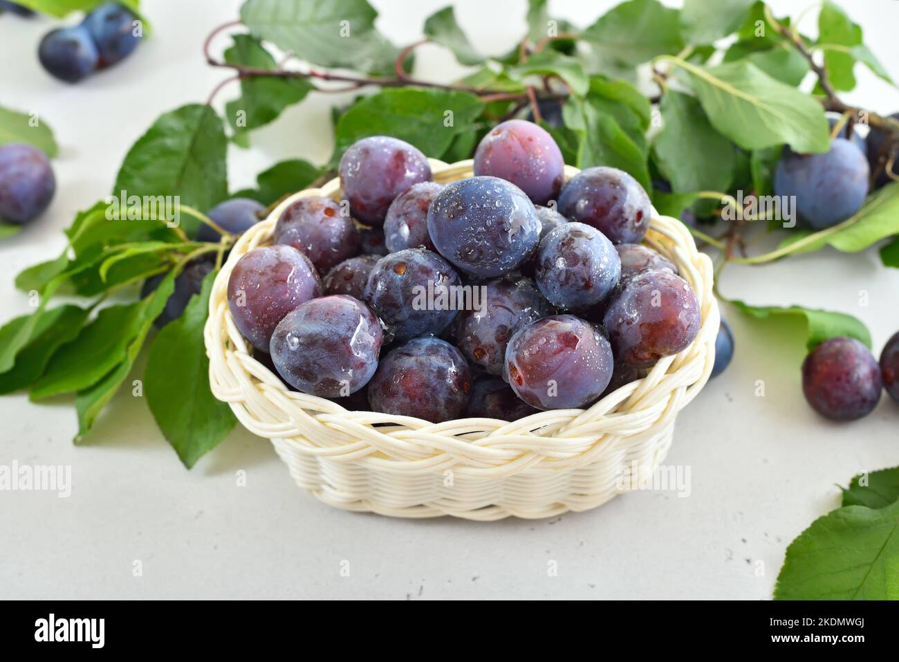 Fresh plums in the basket on stone background Stock Photo - Alamy