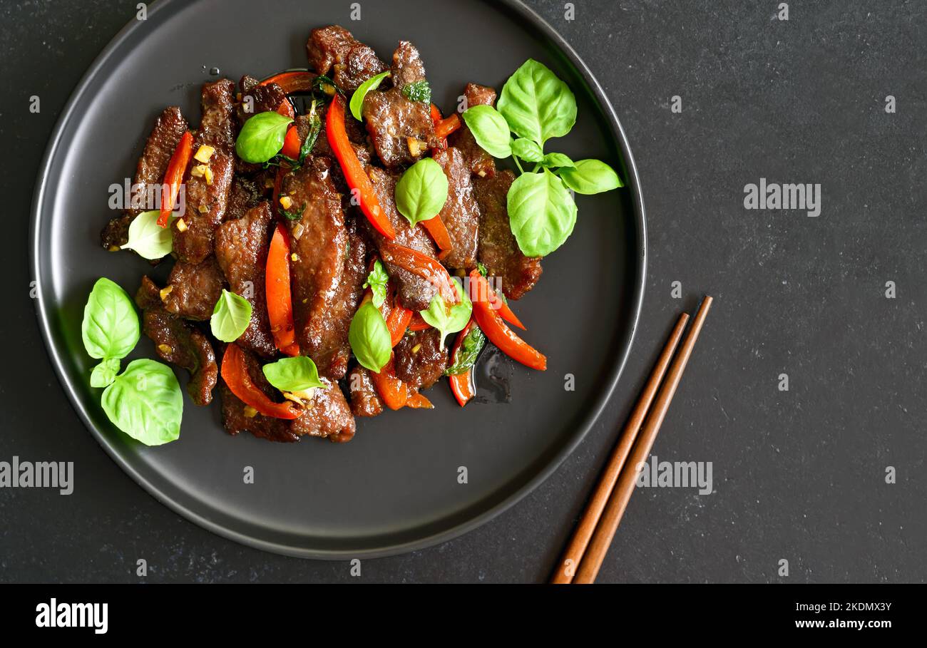 Thai style stir-fry beef with vegetables over dark stone background ...