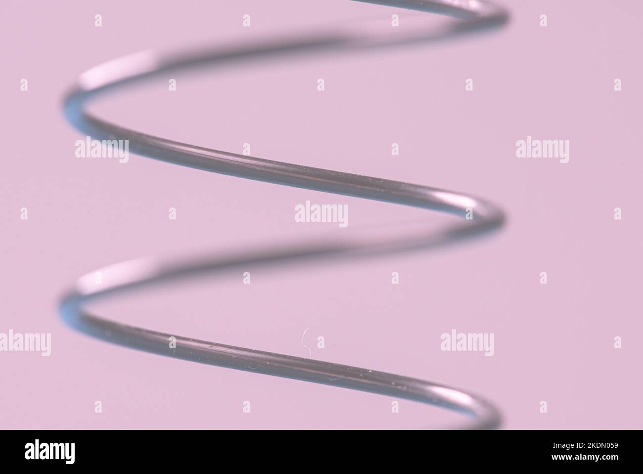 Details of a metal spring on pink cloth Stock Photo - Alamy