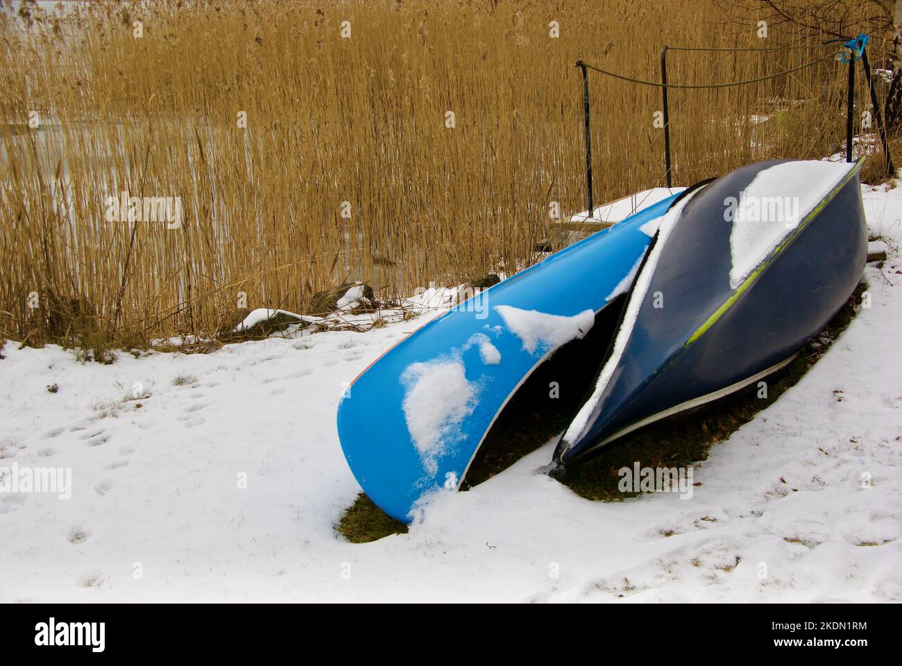 Two blue canoes lying in the snow on the beach in winter Stock Photo ...