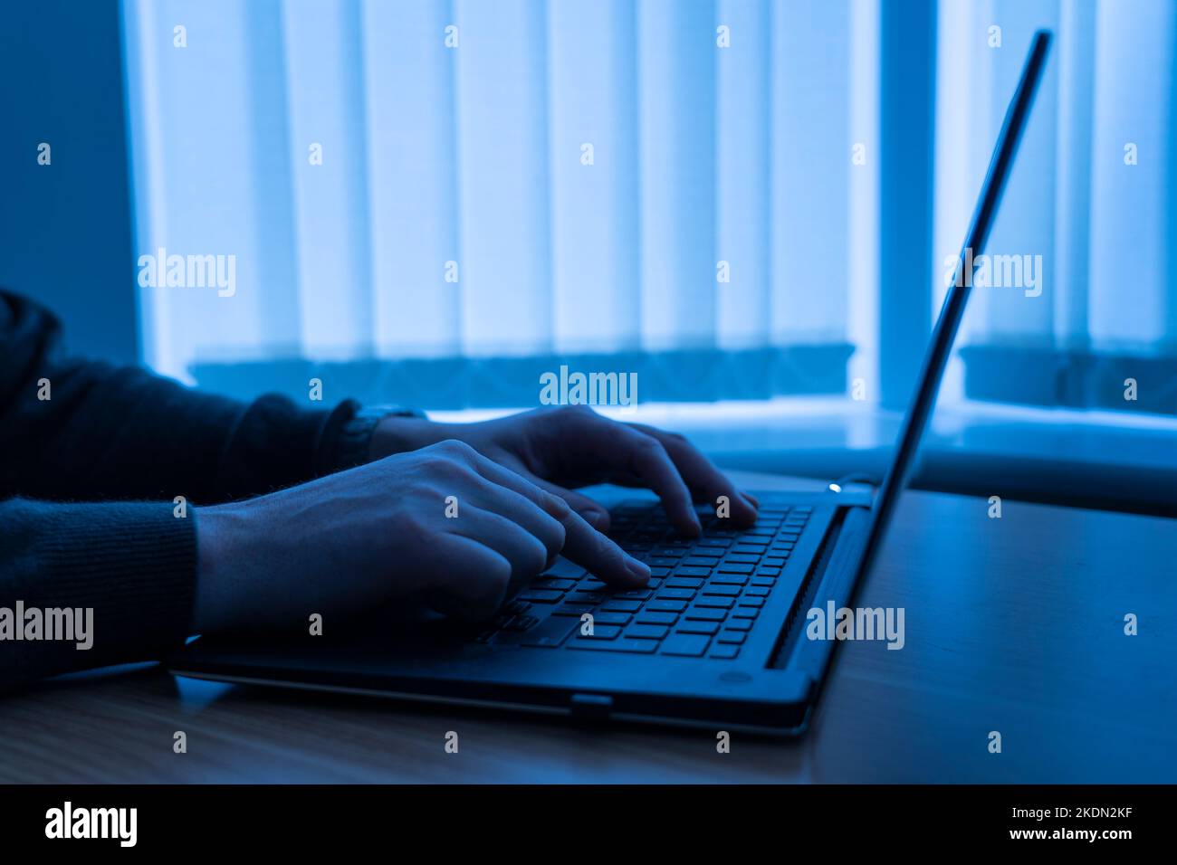 A middle aged man typing on a laptop keyboard. Concept: loneliness ...