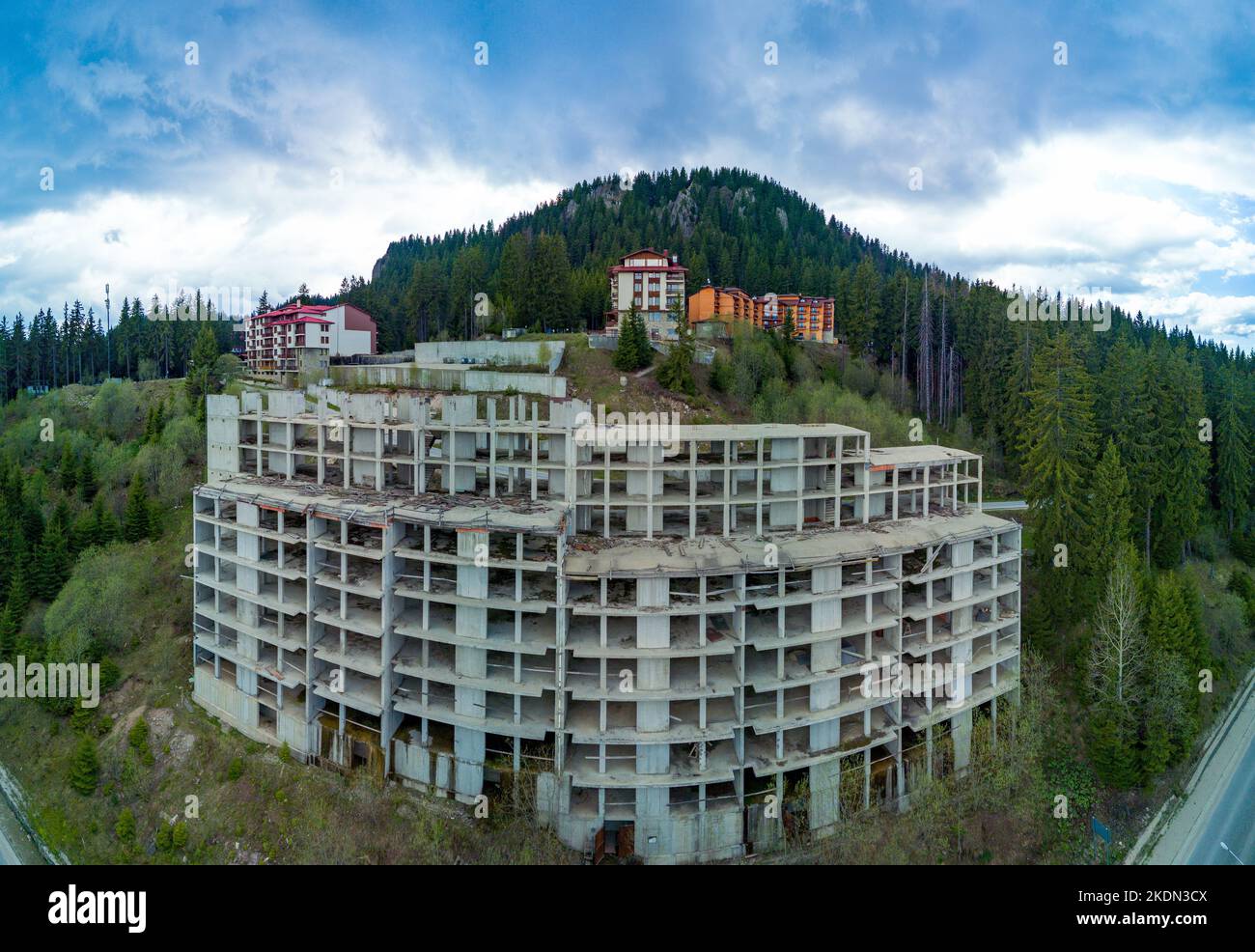 Multi-storey abandoned hotel with concrete walls stands in dense spruce ...