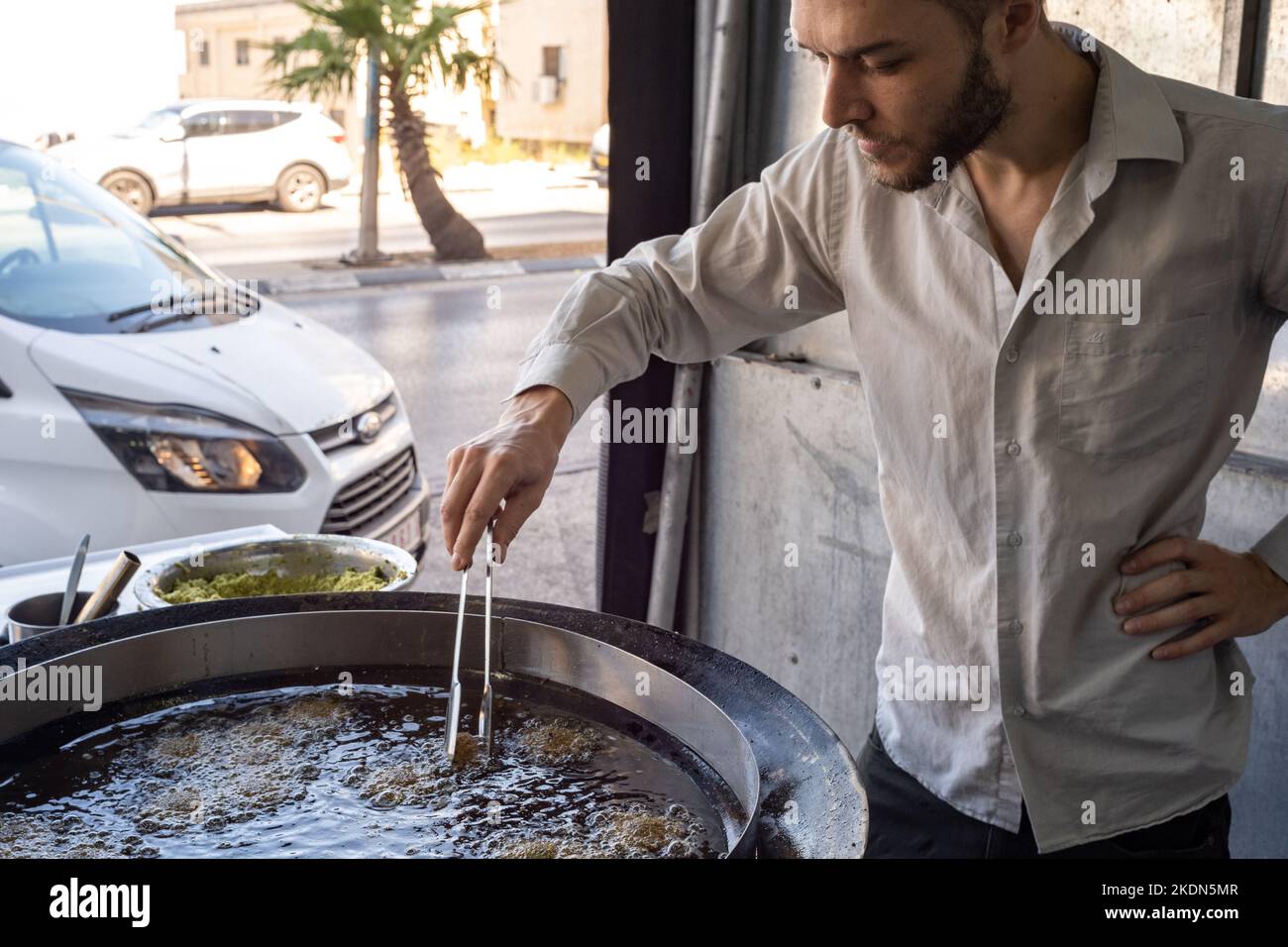 Young White Man in Grey Shirt Moves a Clamp and Fries Falafel Balls in ...