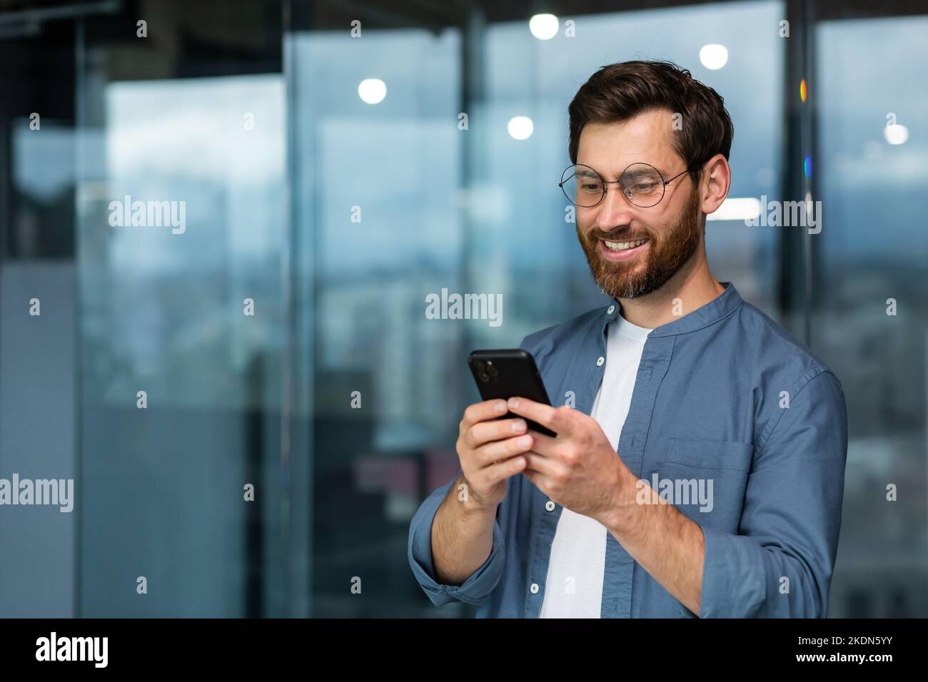 Successful businessman in glasses and beard standing near window in the ...