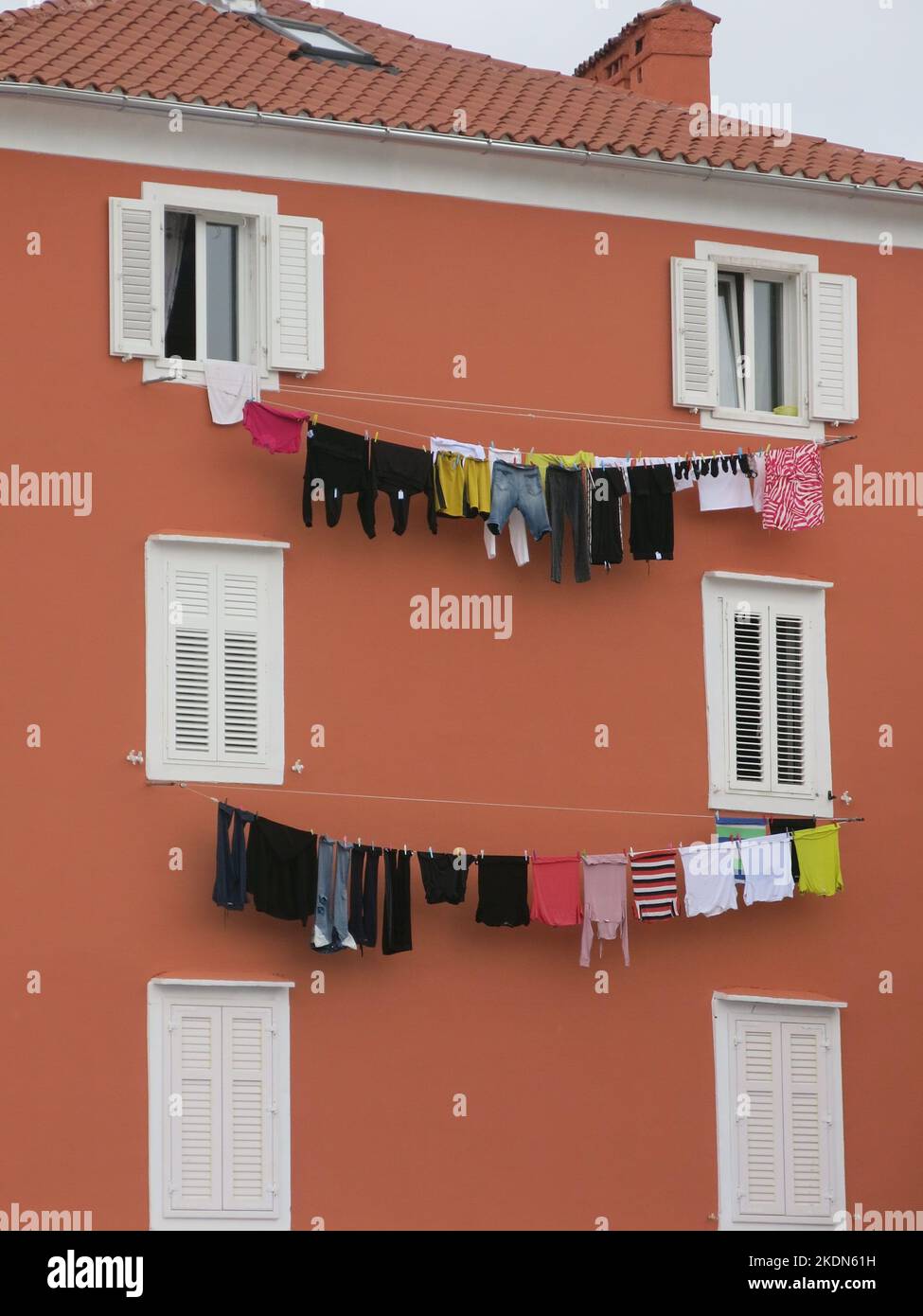Strings of washing are hung out to dry on wires between the windows of ...