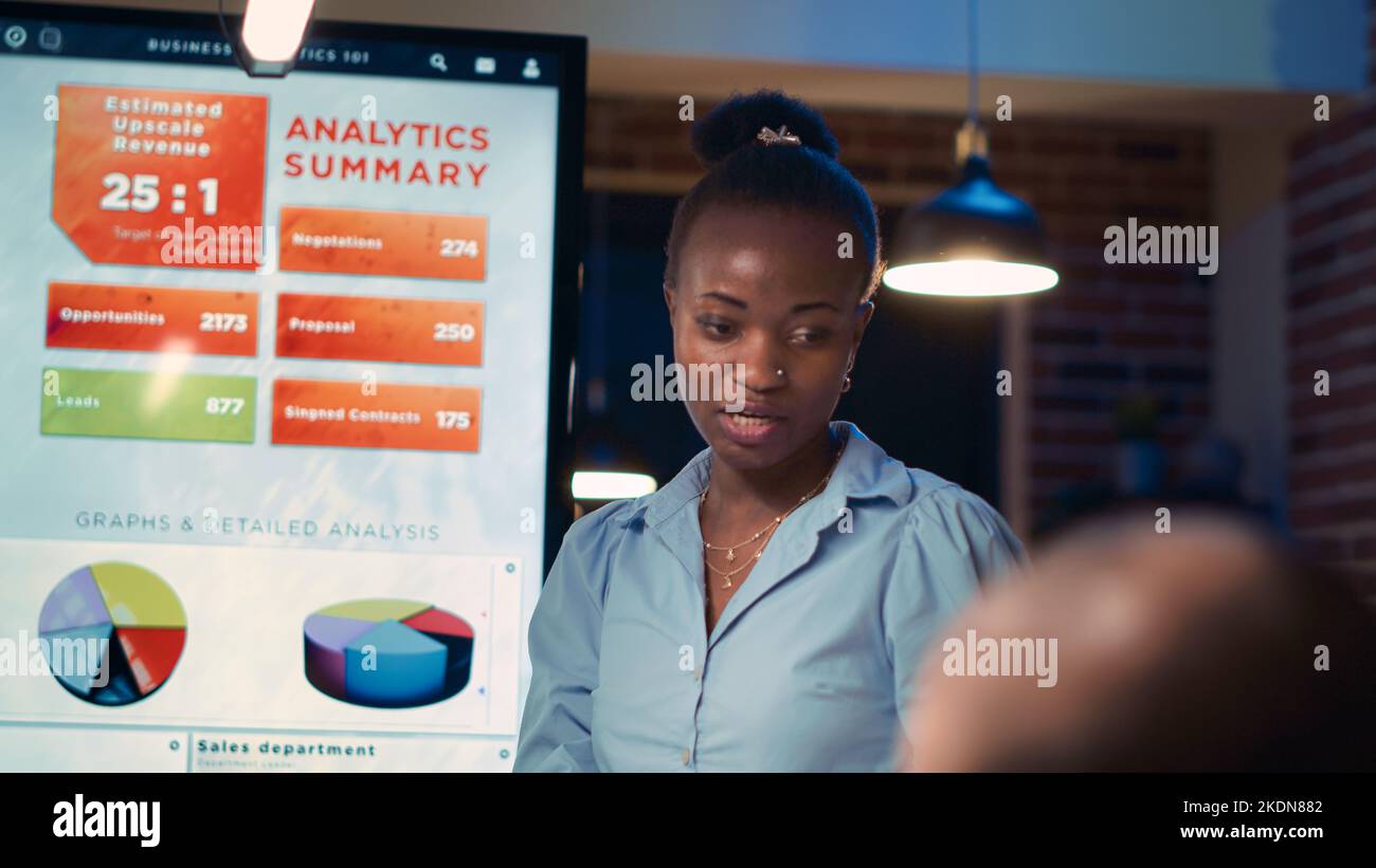 Businesswoman reading report, giving presentation in business meeting, holding clipboard close ...